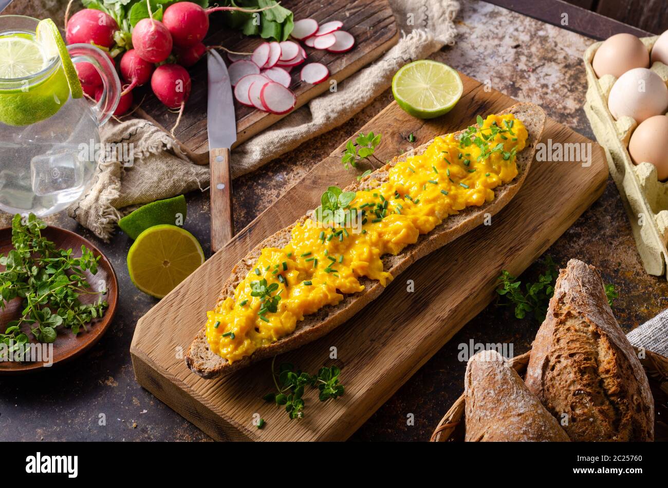 Bio scrambled eggs on rustic french baguette with fresh herbs and ...