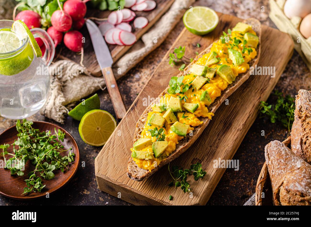 Bio scrambled eggs on rustic french baguette with fresh herbs and ...
