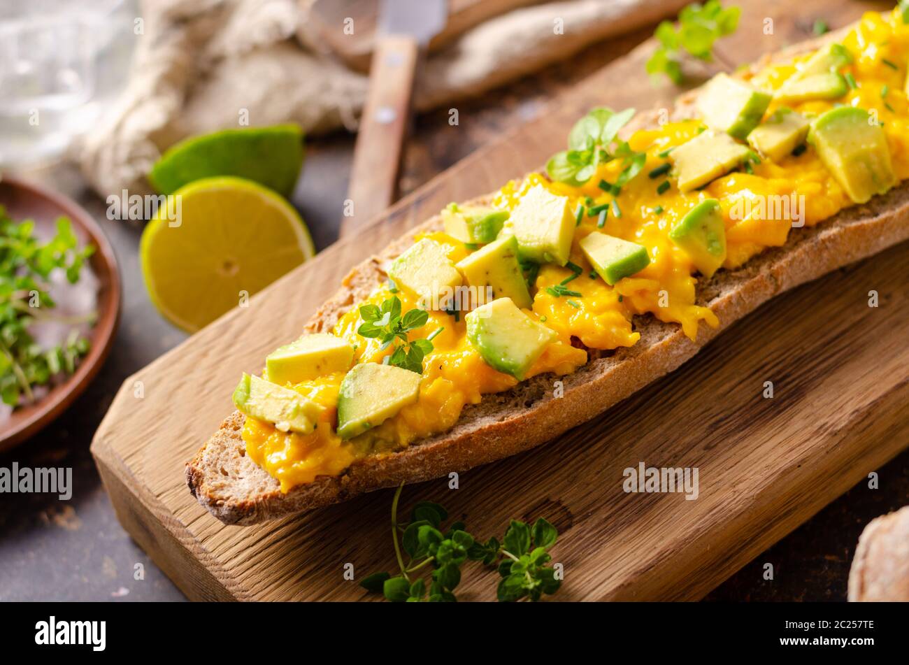 Bio scrambled eggs on rustic french baguette with fresh herbs and ...