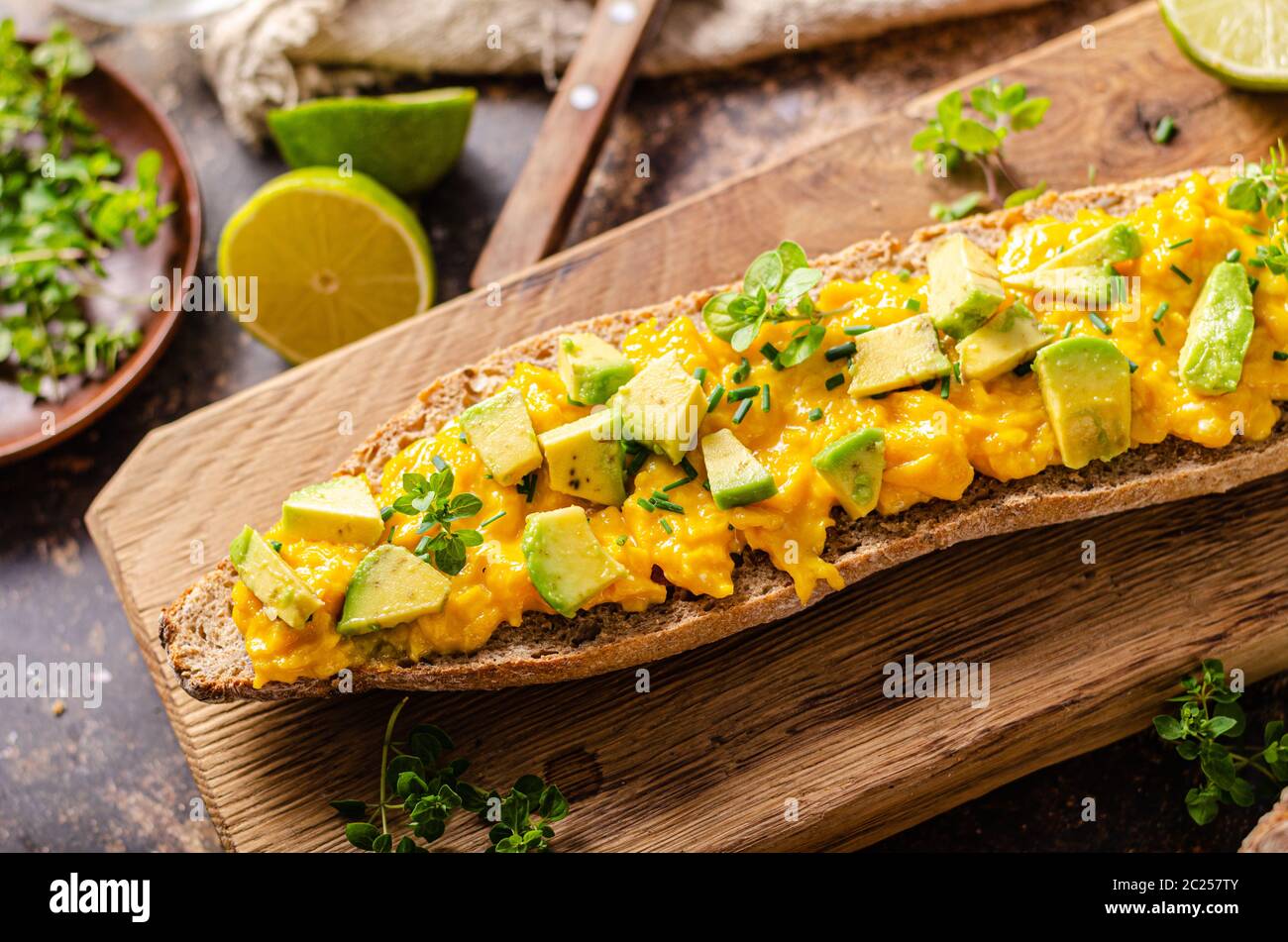 Bio scrambled eggs on rustic french baguette with fresh herbs and ...