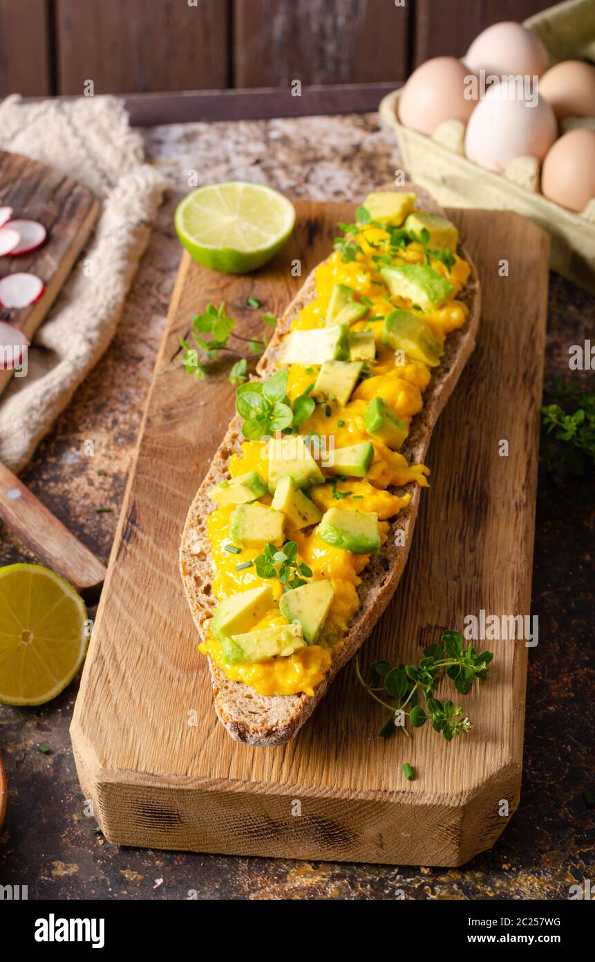Bio scrambled eggs on rustic french baguette with fresh herbs and ...