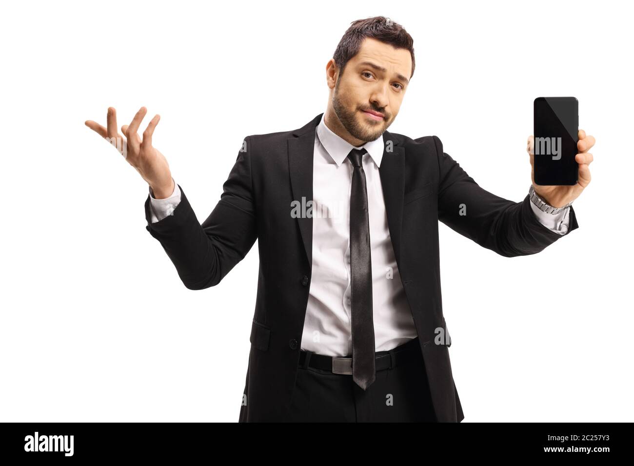 Confused young man in a suit holding a mobile phone isolated on white ...