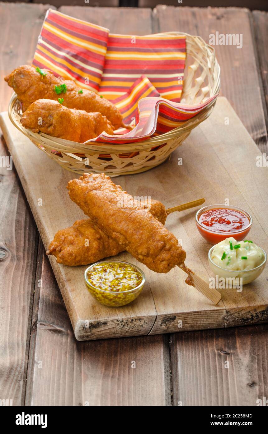 Corn dog with three sauces, chilli, mayonnaise with herbs and whole ...