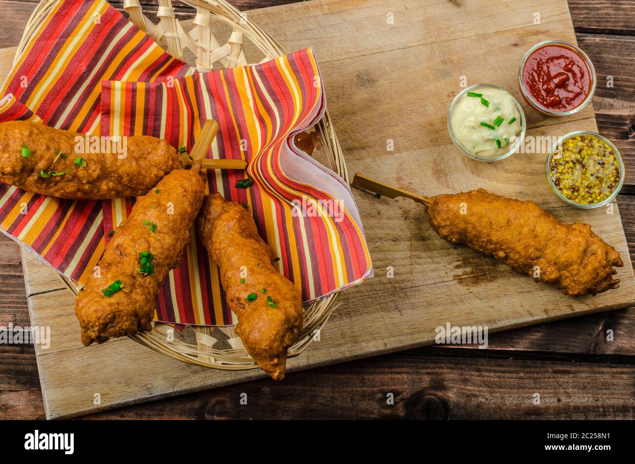 Corn dog with three sauces, chilli, mayonnaise with herbs and whole ...