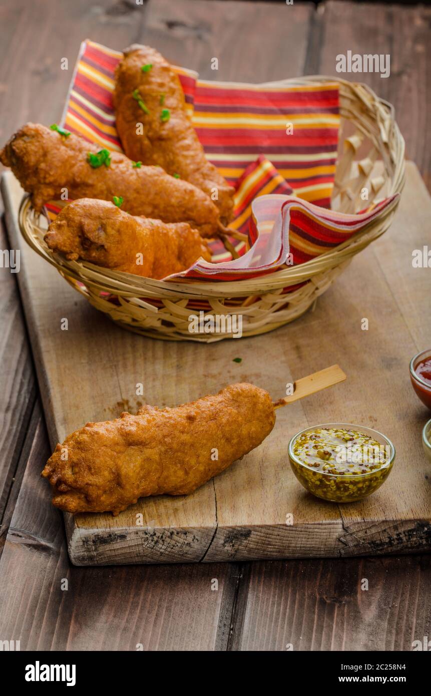 Corn dog with three sauces, chilli, mayonnaise with herbs and whole ...