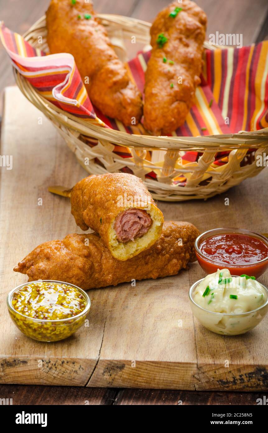 Corn dog with three sauces, chilli, mayonnaise with herbs and whole ...