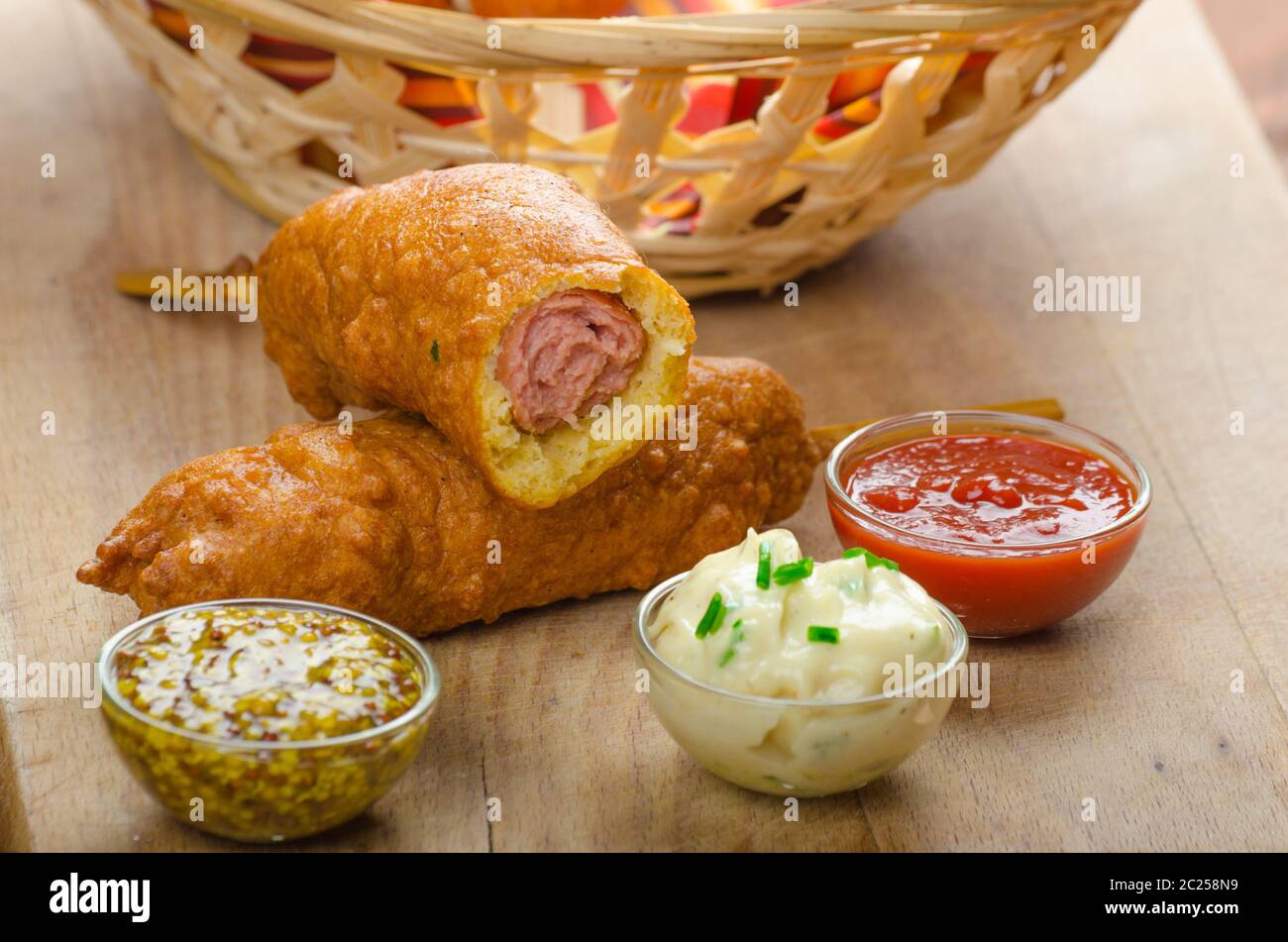 Corn dog with three sauces, chilli, mayonnaise with herbs and whole ...