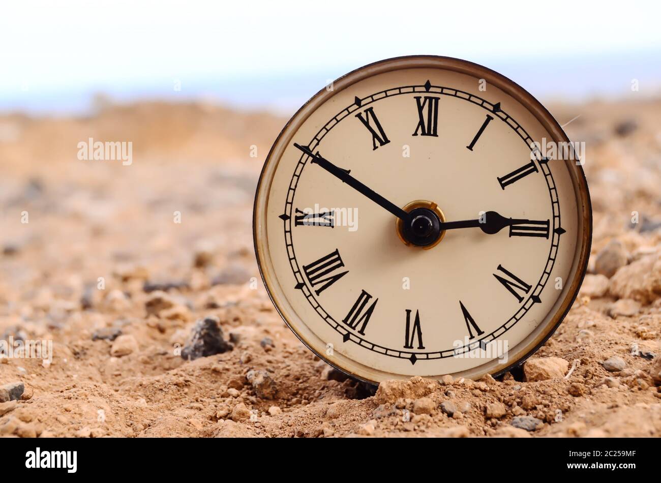 Classic Analog Clock In The Sand On The Rock Desert Stock Photo - Alamy