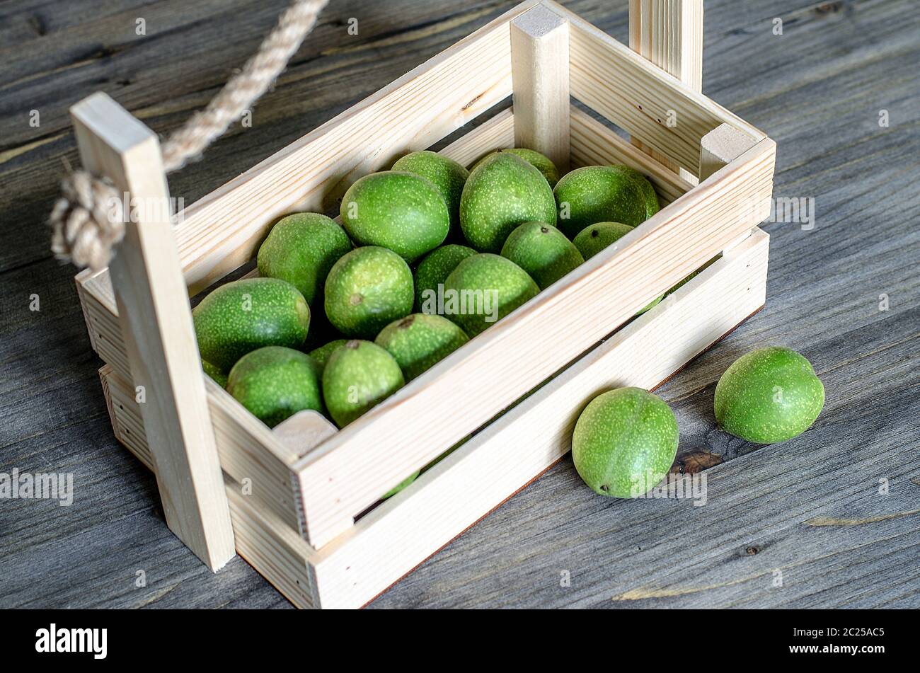 Young fruits of walnuts in a green shell in a wooden box Stock Photo ...