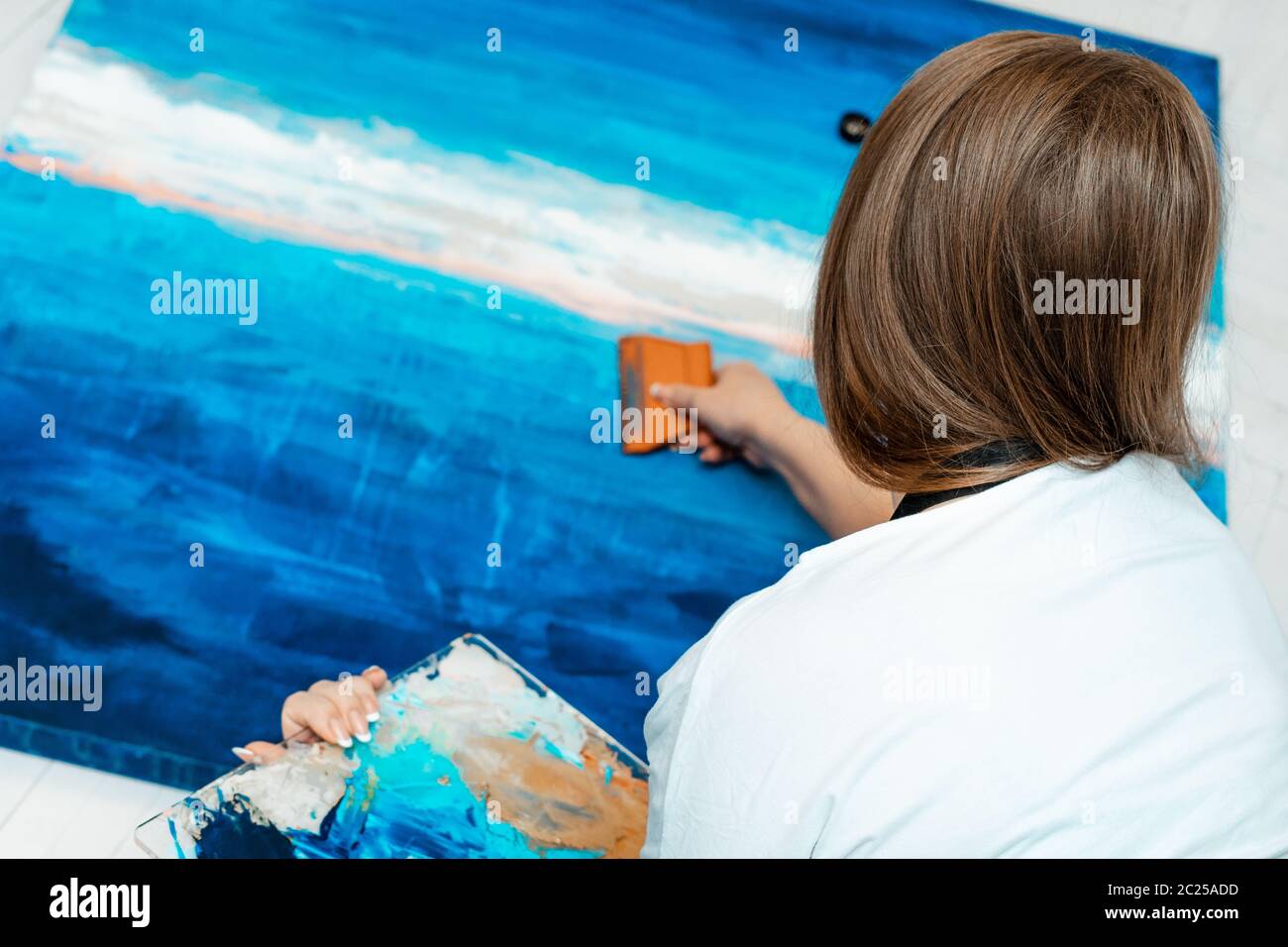 Art, the work of the artist. Young beautiful girl artist paints a ...