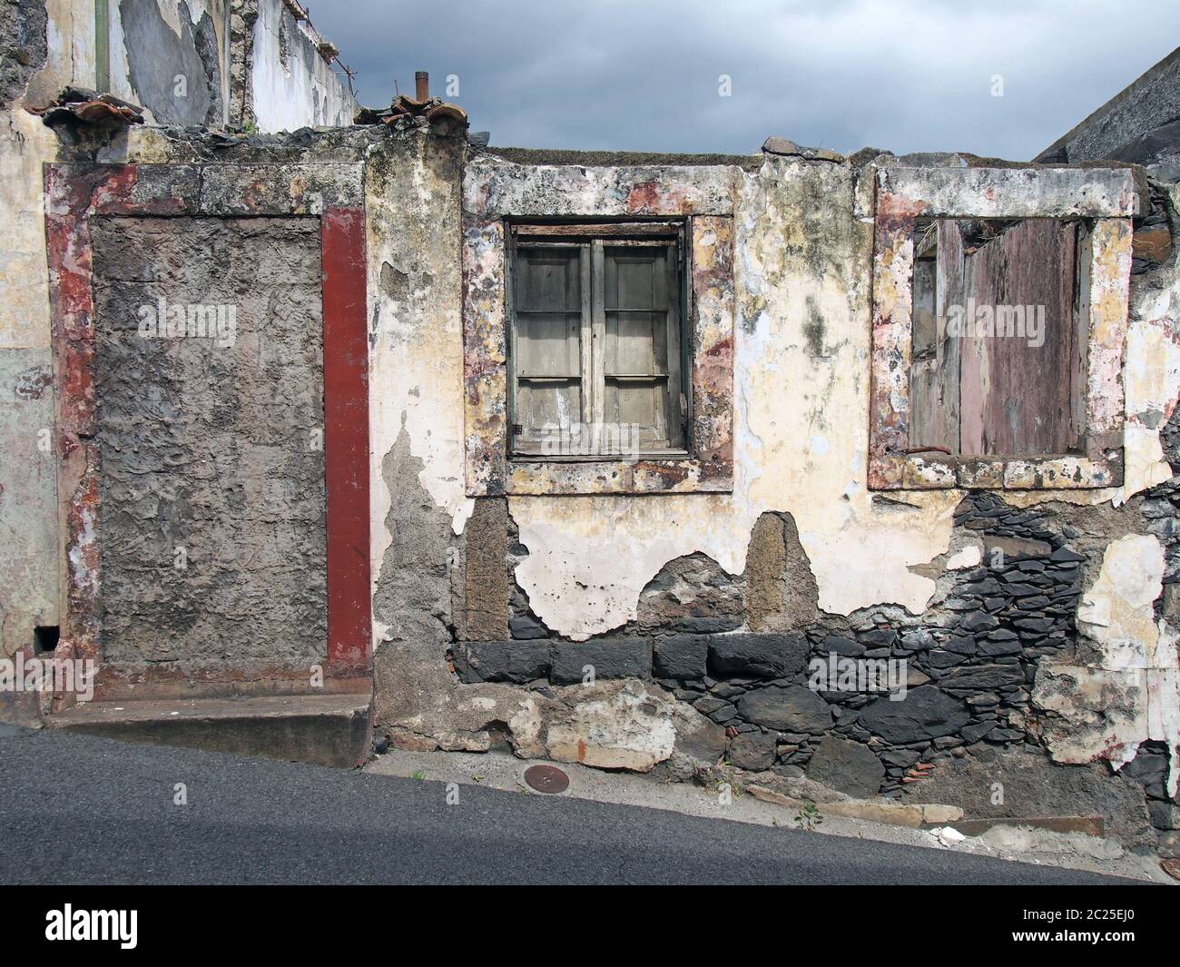 an old ruined house partly collapsed on a sloping street with a blocked ...