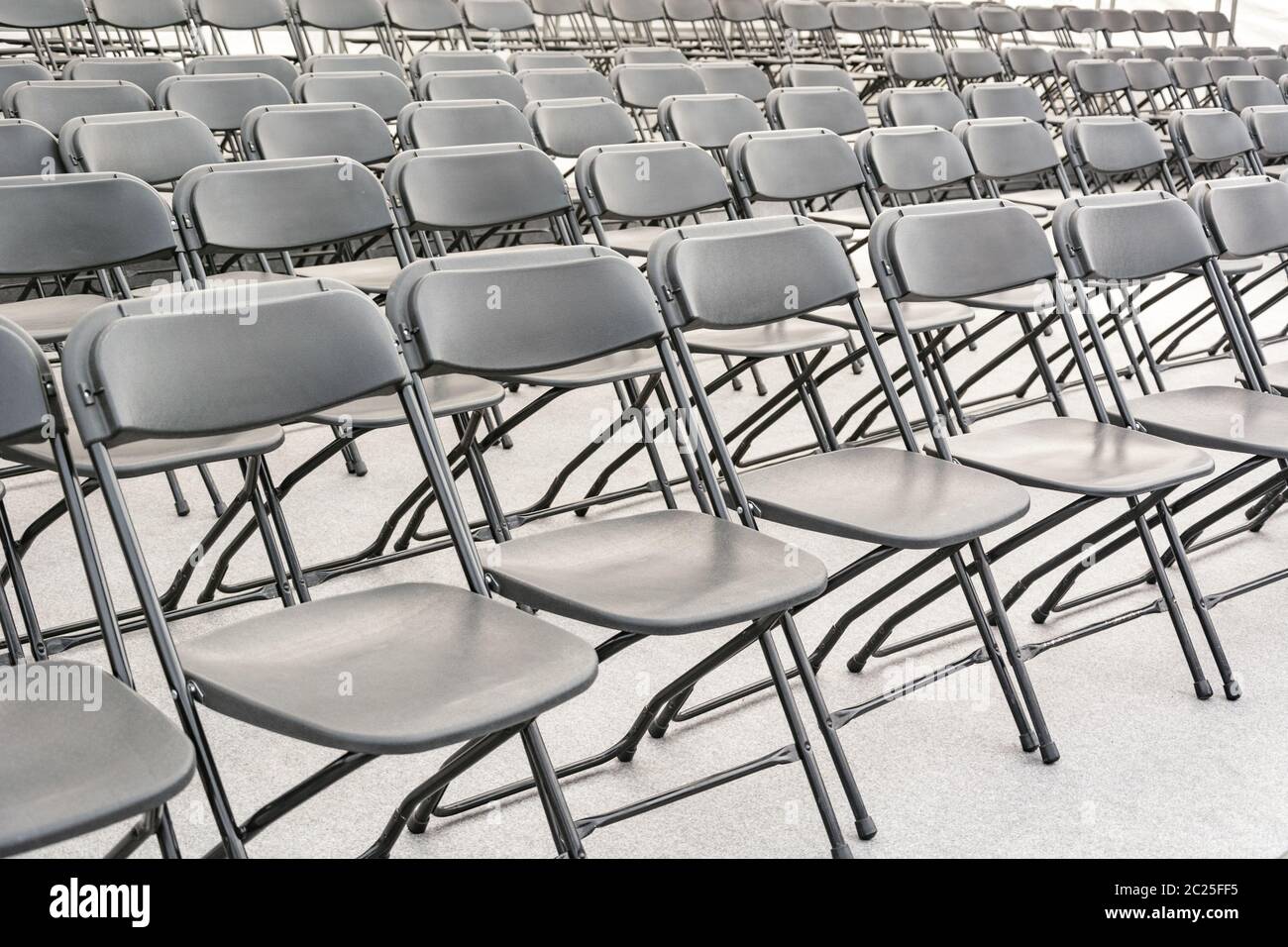 Rows of black folding chairs empty Stock Photo - Alamy