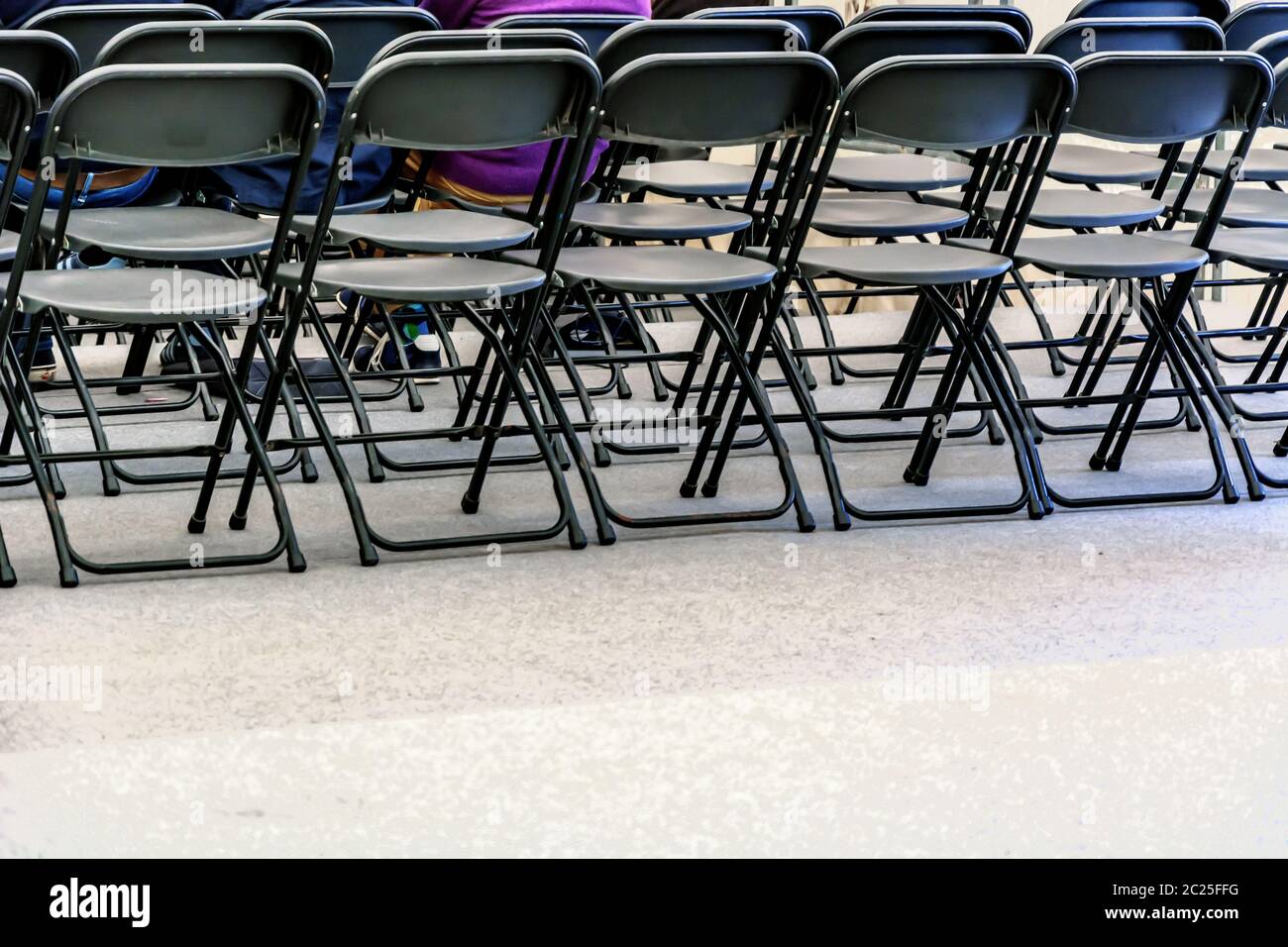 Rows of black folding chairs empty Stock Photo - Alamy