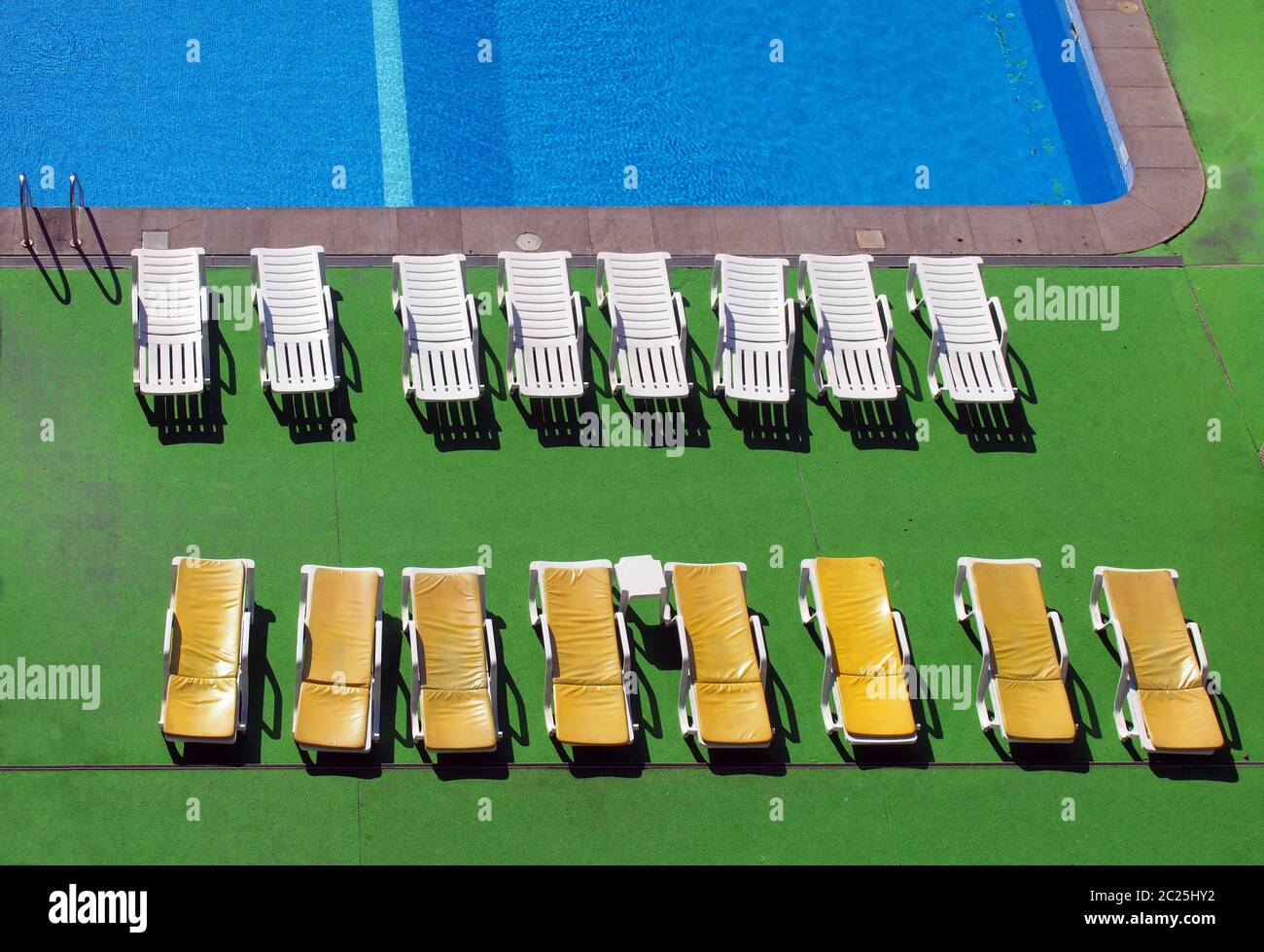 view of an outdoor swimming pool from above with sun loungers an sunlit ...