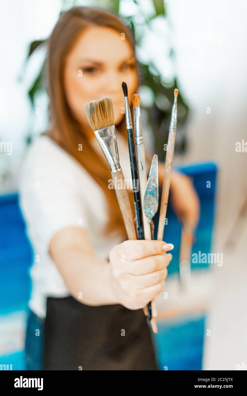 Art, the work of the artist. Young beautiful girl artist paints a ...