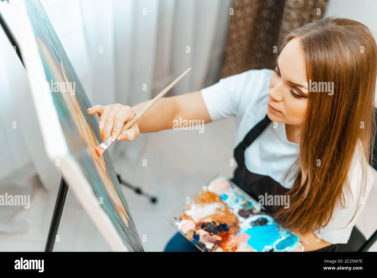 Art, the work of the artist. Young beautiful girl artist paints a ...