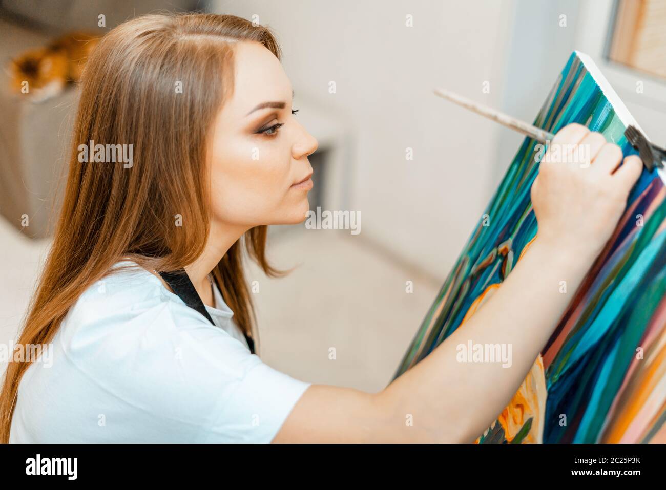 Art, the work of the artist. Young beautiful girl artist paints a ...