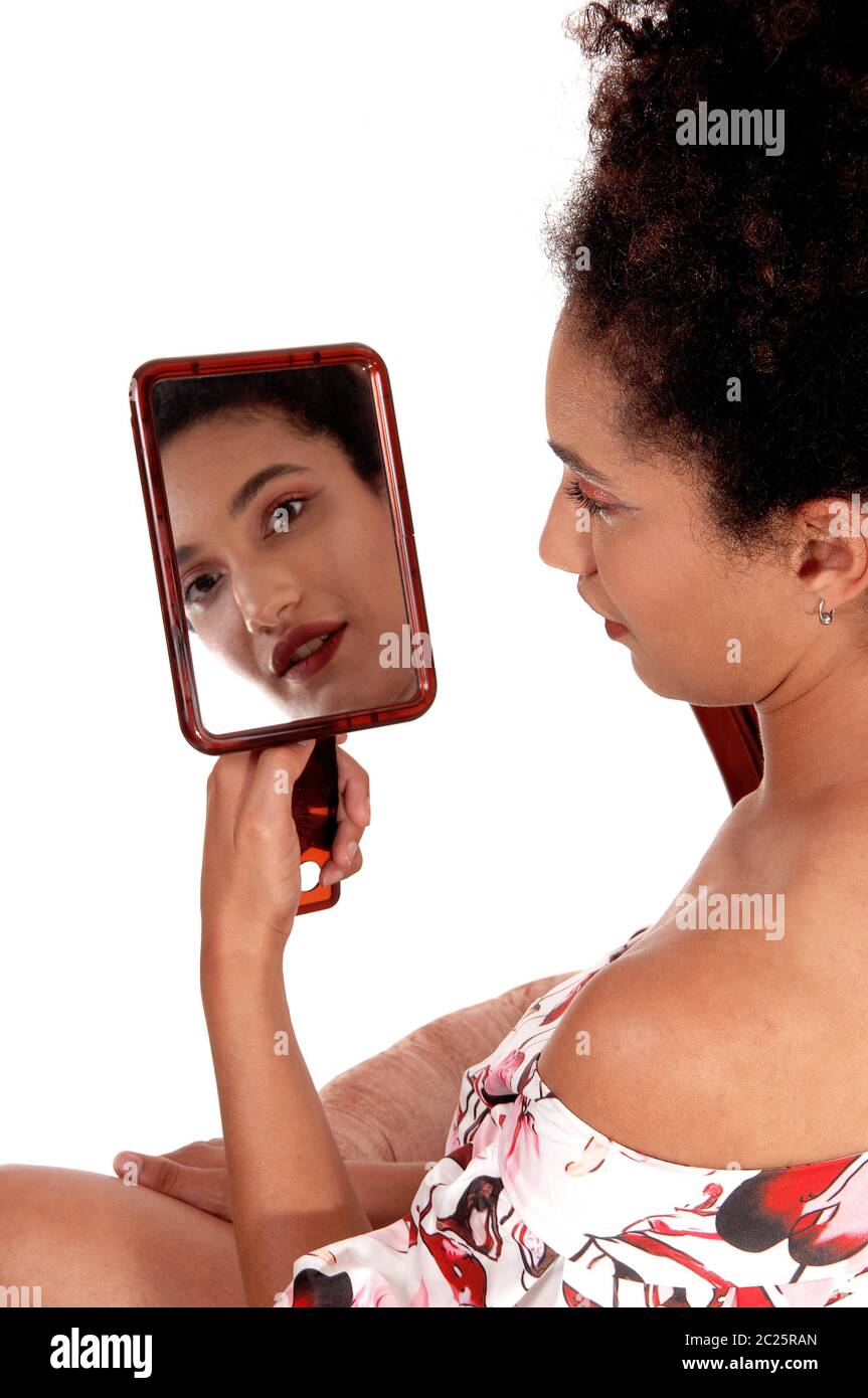 Lovely multi-racial woman looking at herself in a hand held mirror ...