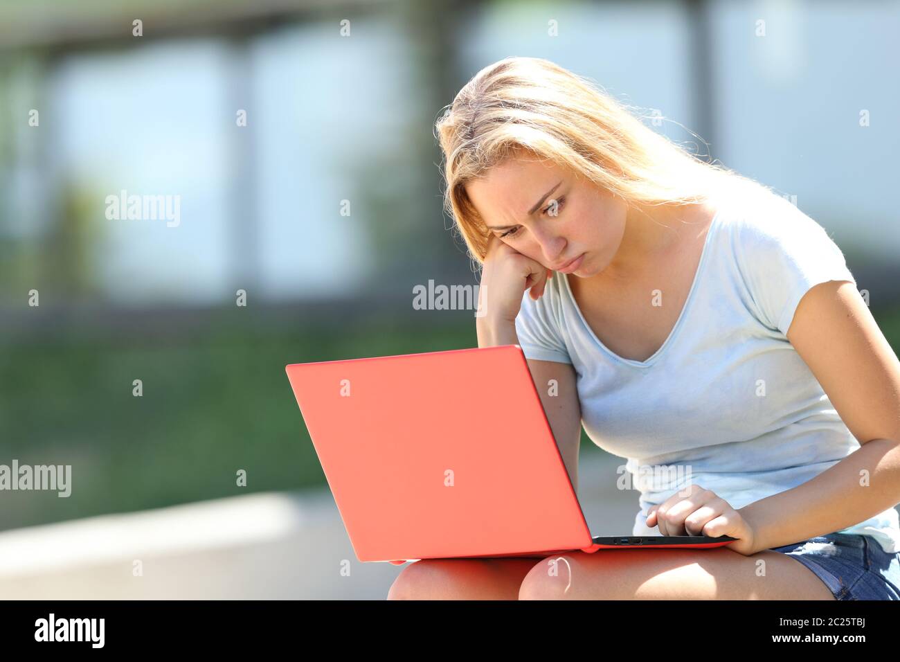 Frustrated student studying a difficult lesson using laptop outdoors in ...