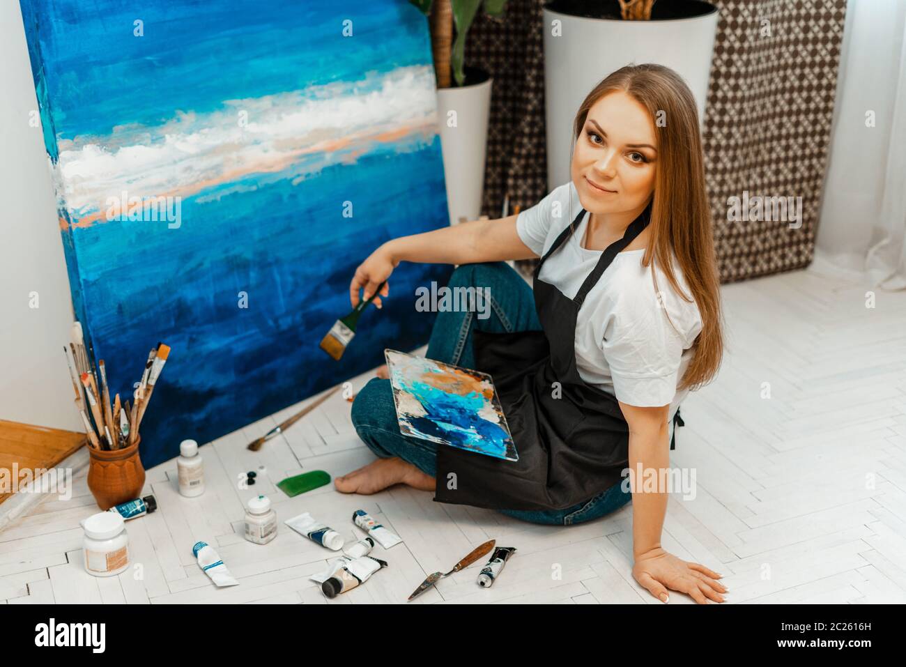 Art, the work of the artist. Young beautiful girl artist paints a ...