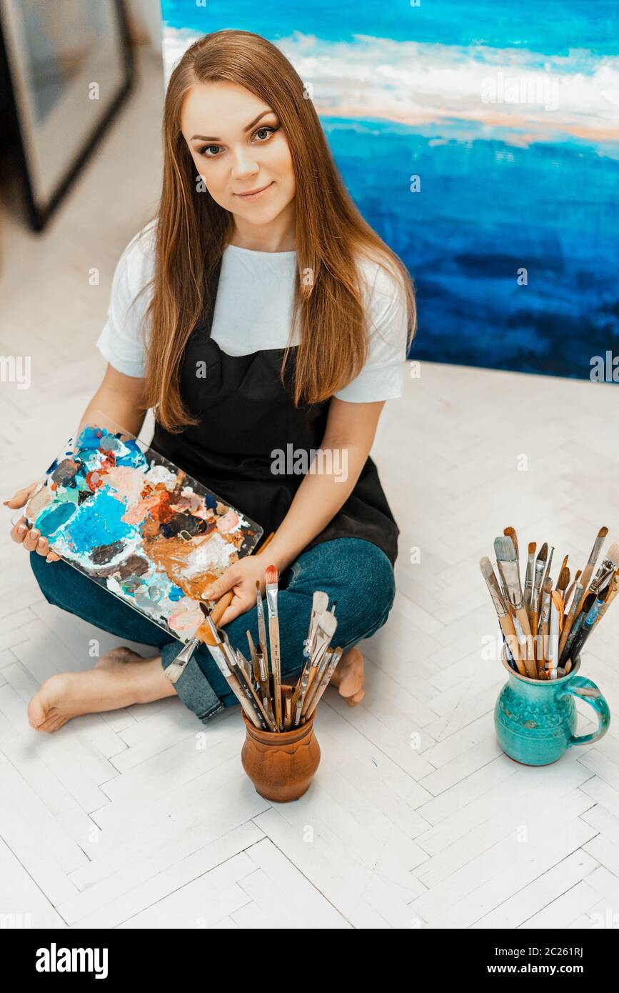 Art, the work of the artist. Young beautiful girl artist paints a ...