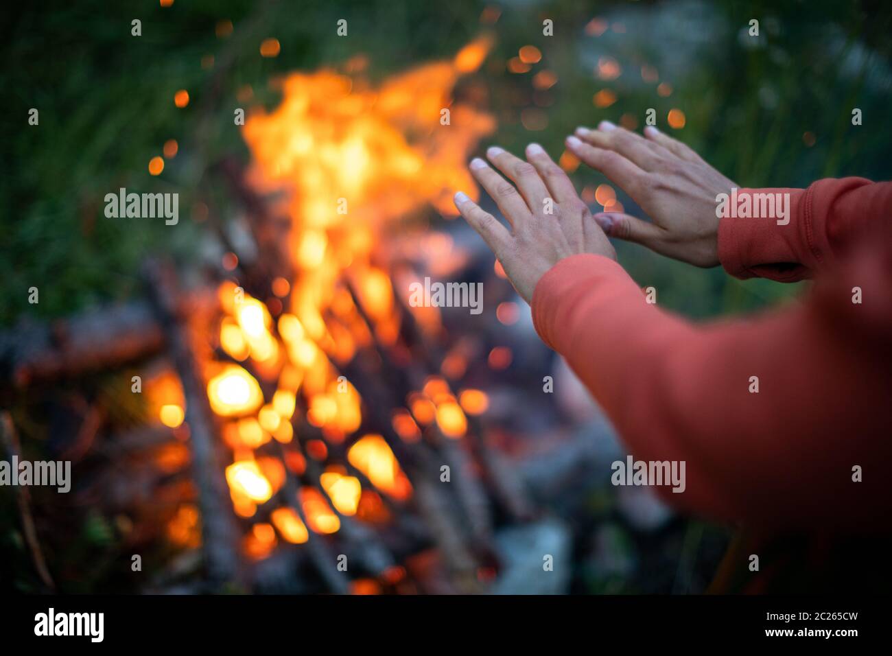 Young woman making fire while camping outdoors, in an alpine wilderness ...