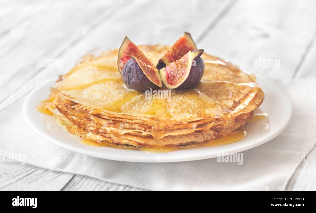 Stack of homemade crepes with fresh fig and sweet topping on the white ...