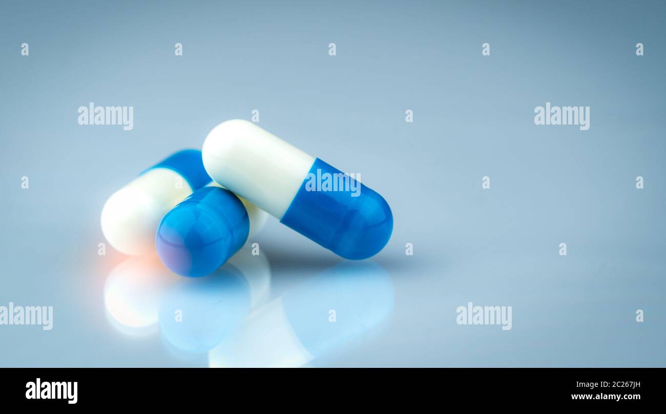 Blue and white capsule pills on gradient background. Global healthcare ...