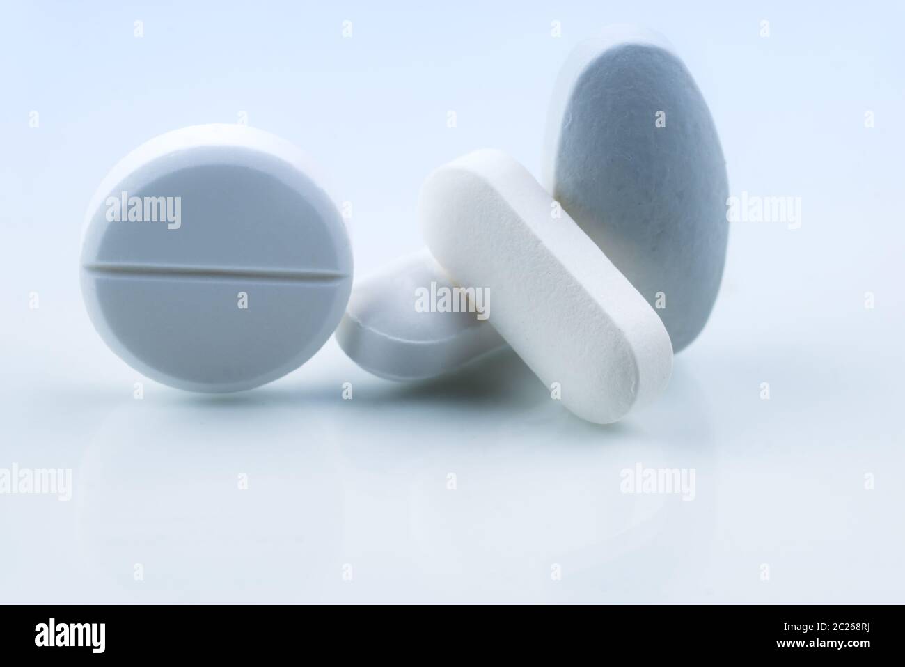 Pile of white round and oblong shape tablet pills isolated on white ...