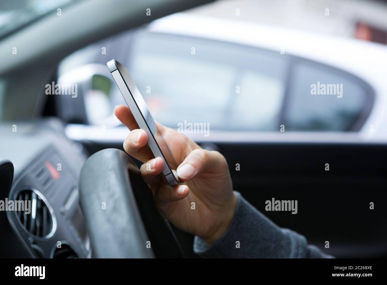 Hand using phone sending a text while driving to work Stock Photo - Alamy