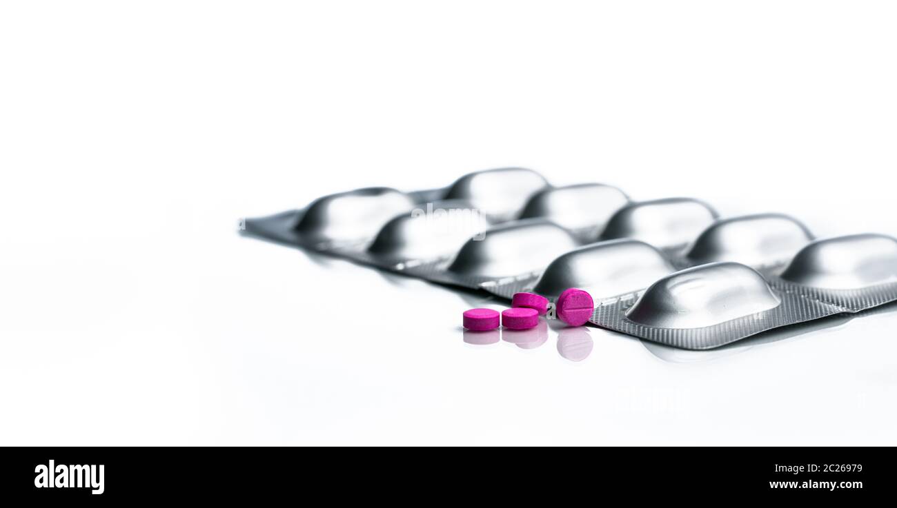 Macro shot of small pink tablets pills and silver aluminium foil ...