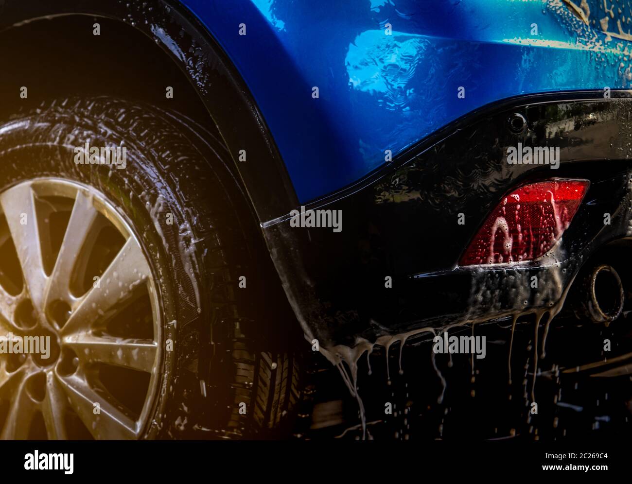 Blue compact SUV car with sport design are washing with water and soap ...