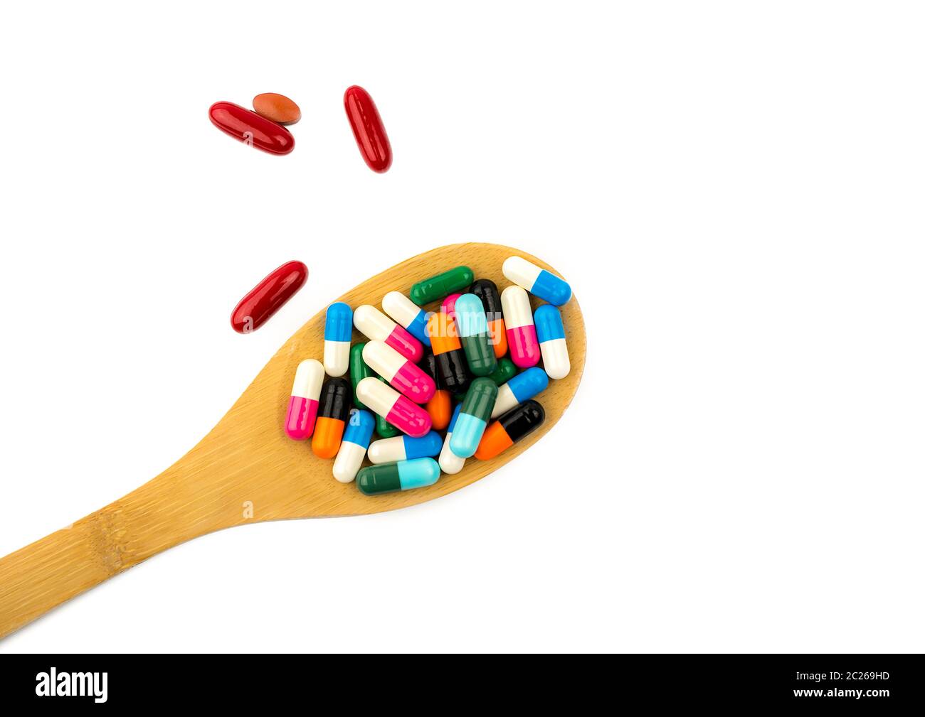 Colorful of capsule pills in wooden spoon are spilling isolated on ...