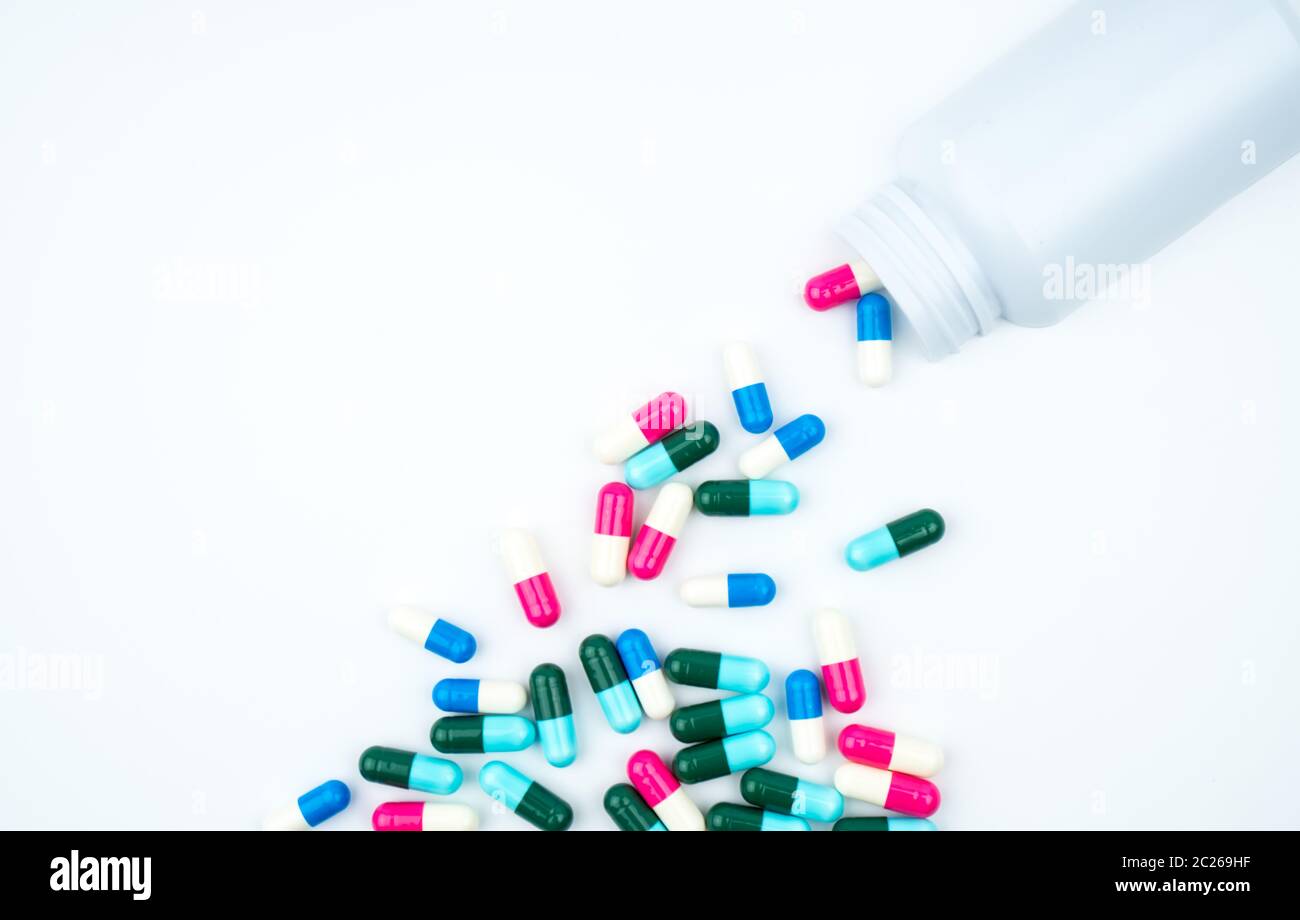 Antibiotic capsules spilling out of pill bottle on white background ...