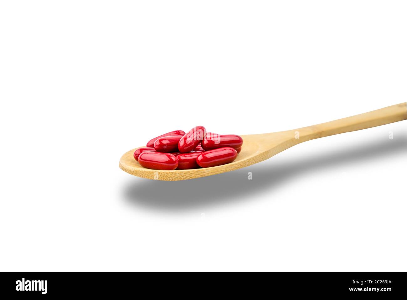 Red vitamins and supplements capsule on wooden spoon isolated on white ...
