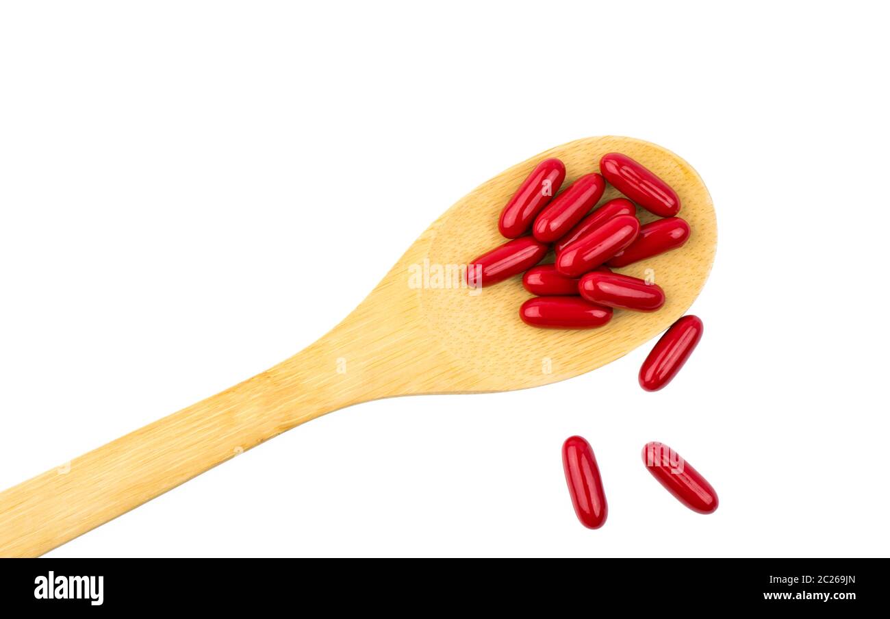 Red vitamins and supplements capsule on wooden spoon isolated on white ...