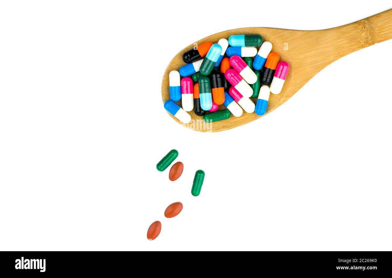 Colorful of capsule pills in wooden spoon are spilling isolated on ...