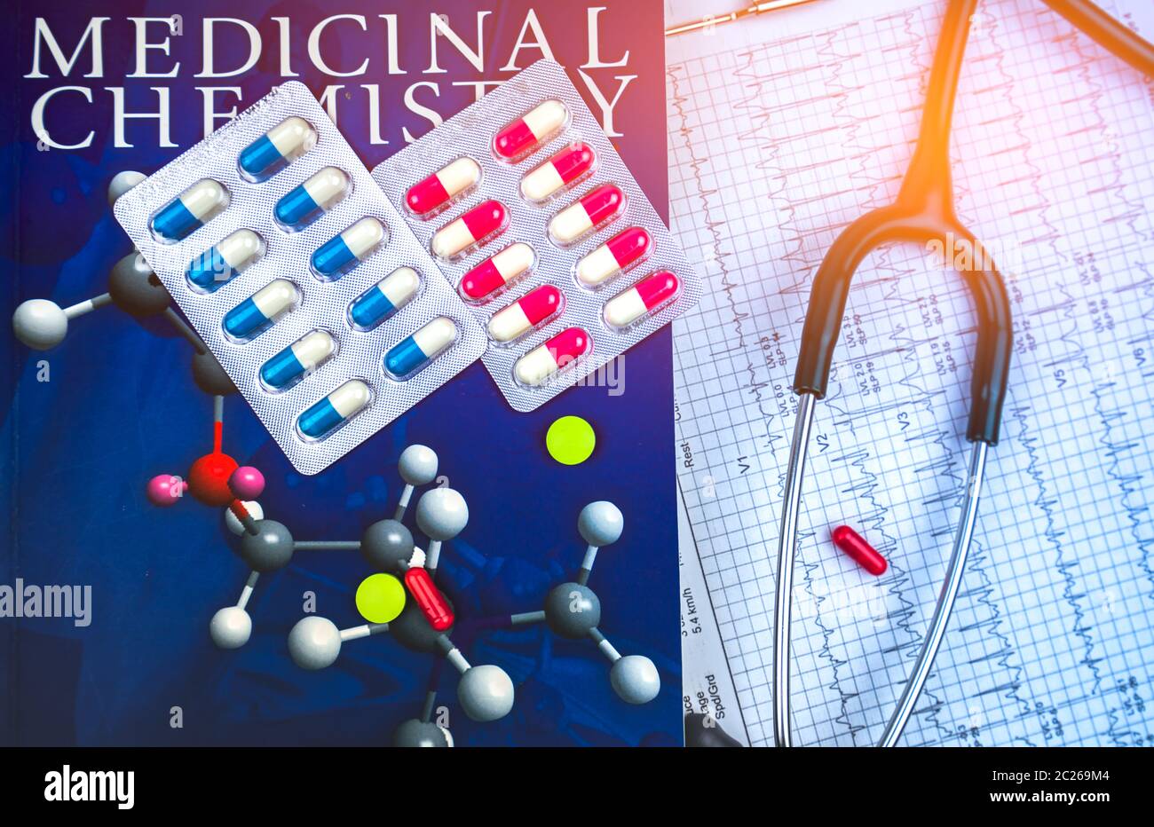 Pills on textbook of medicinal chemistry and stethoscope put on EKG or ...