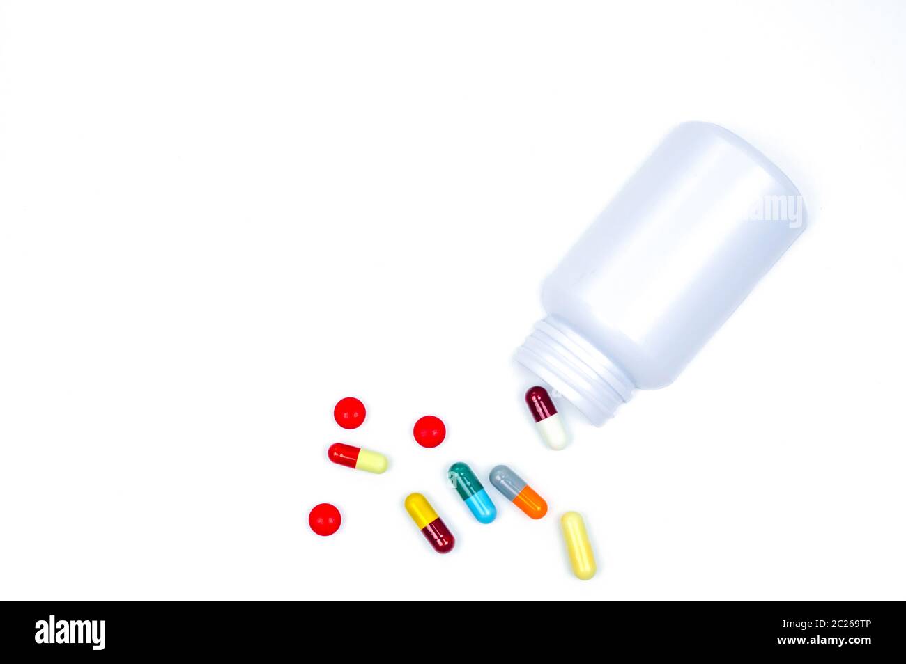 Antibiotic capsules spilling out of pill bottle isolated on white ...