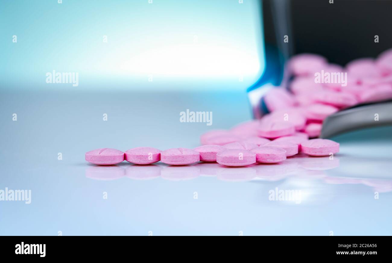Pink tablets pills on blurred background of drug tray. Pharmaceutical ...