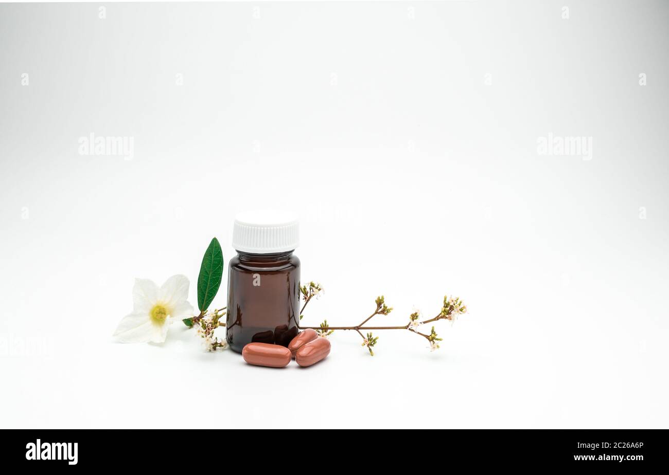 Three orange vitamin and supplement capsule pills with flower and ...