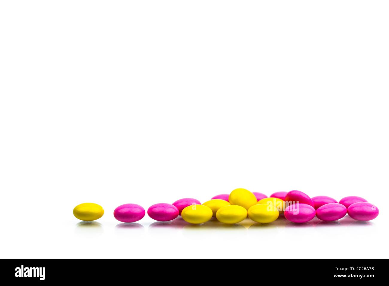 Pile of pink and yellow round sugar coated tablets pills isolated on ...