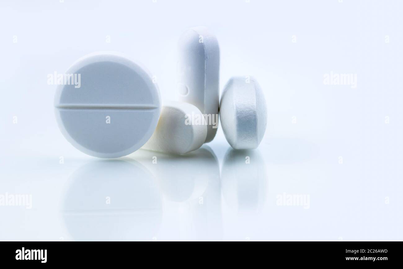Pile of white round and oblong shape tablet pills isolated on white ...
