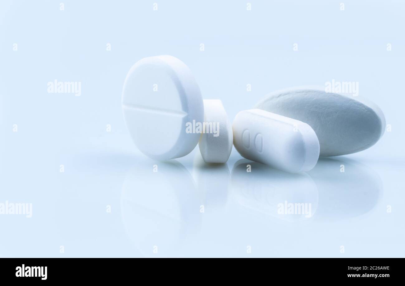 Pile of white round and oblong shape tablet pills isolated on white ...