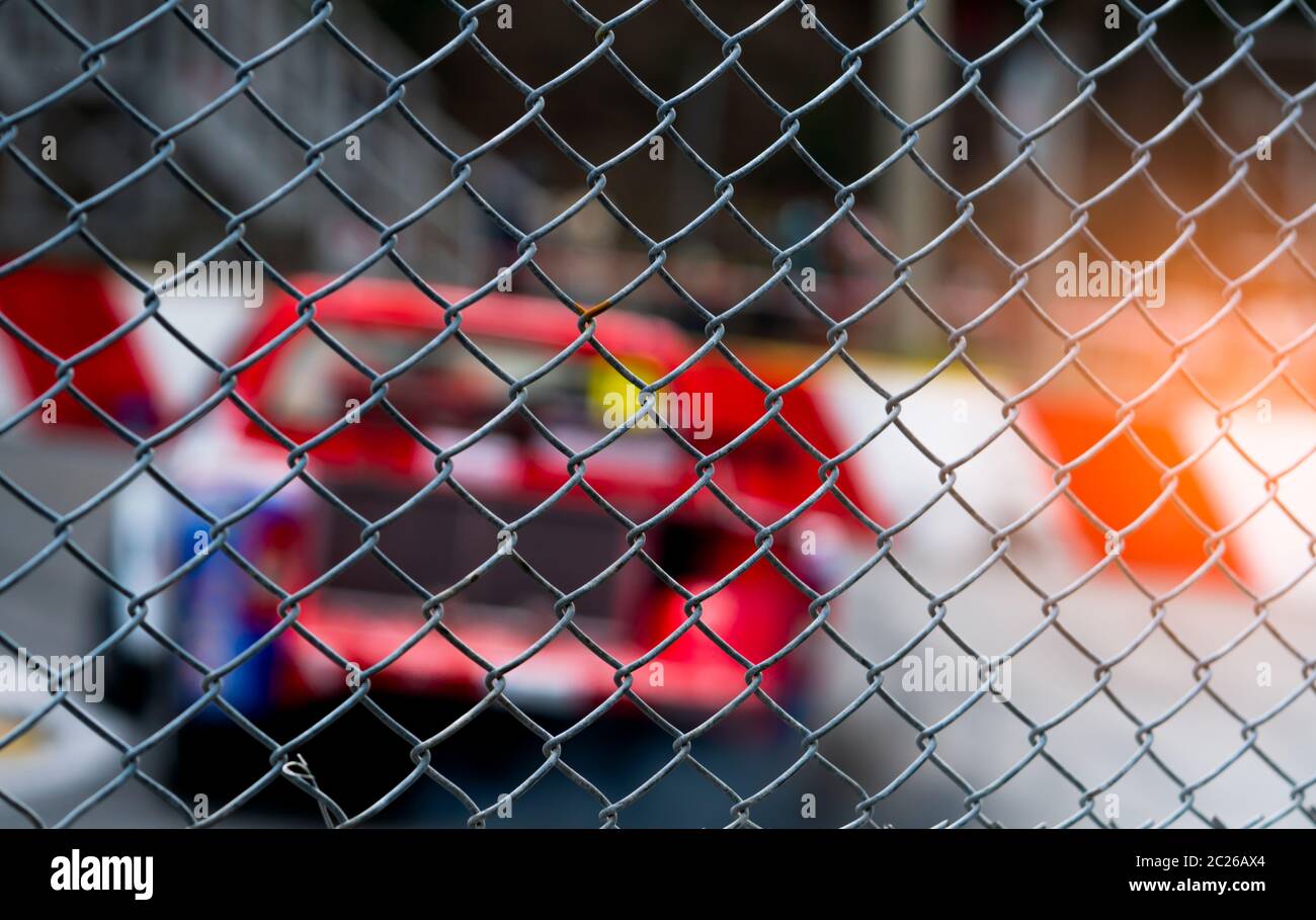 Motorsport car racing on asphalt road. View from the fence mesh netting ...