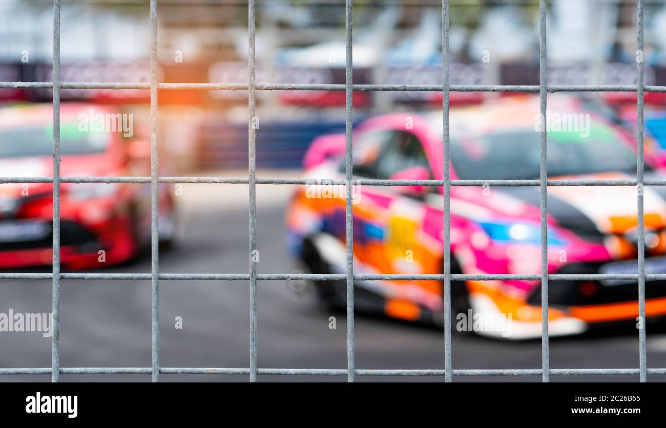 Motorsport car racing on asphalt road. View from the fence mesh netting ...