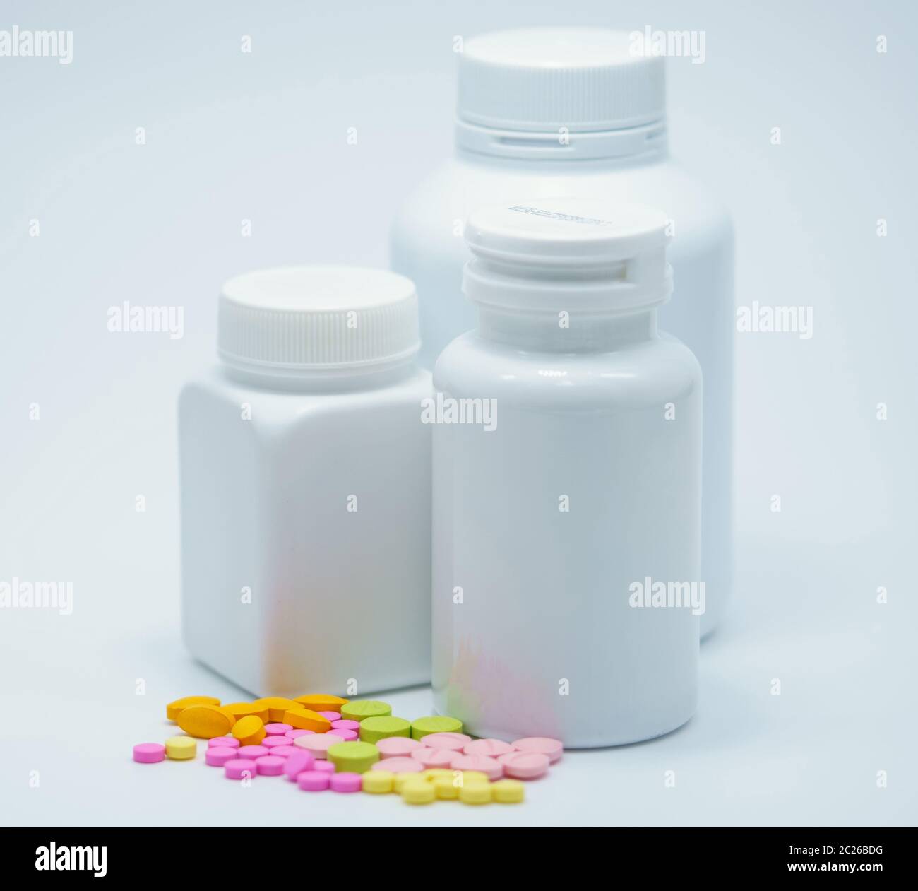 Colorful tablet pills with closed white bottles on white background ...