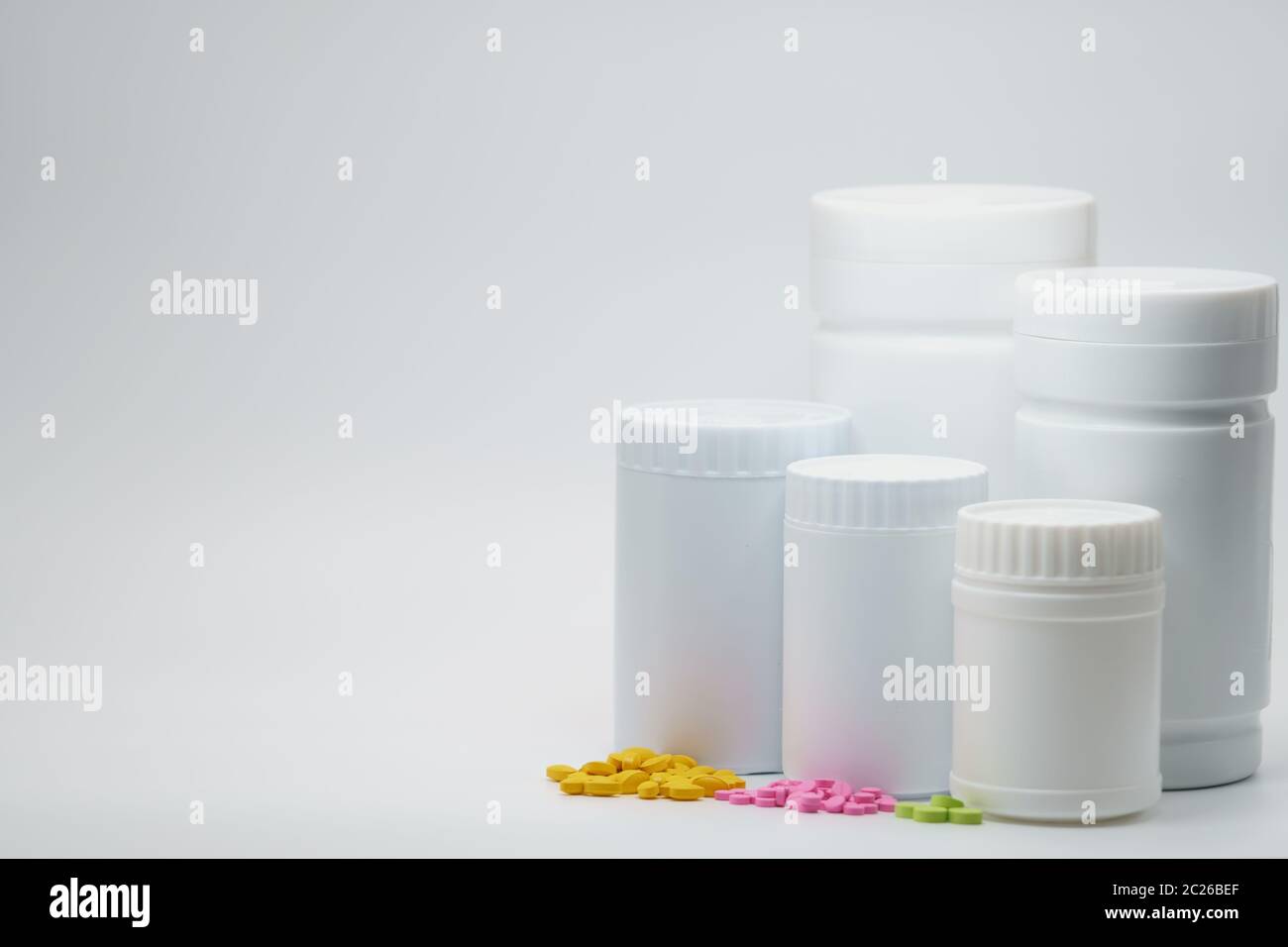 Yellow, pink, and green tablets on white background with drug bottle ...