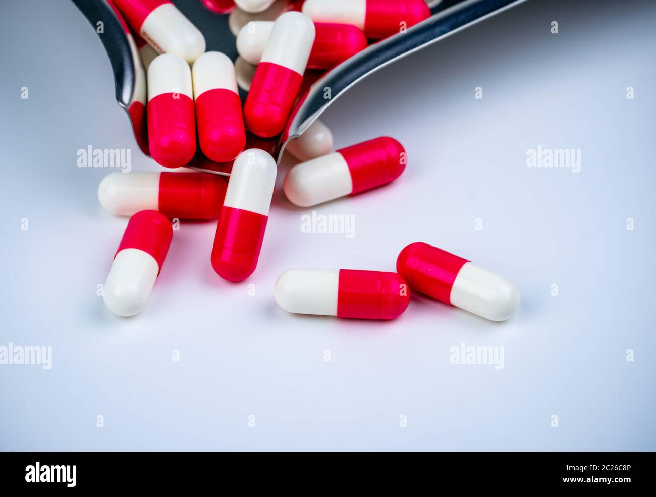 Red-white capsule pills on stainless steel drug tray and some on white ...