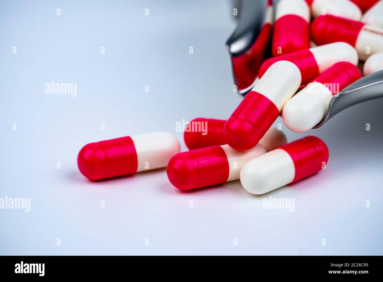 Red-white capsule pills on stainless steel drug tray and some on white ...